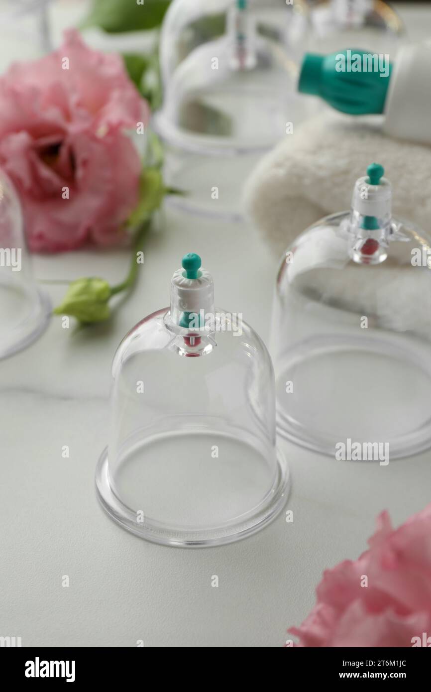 Plastic cups and flowers on white marble table. Cupping therapy Stock ...