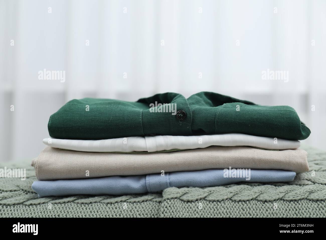 Sorting and organizing. Stack of different folded clothes on bed ...