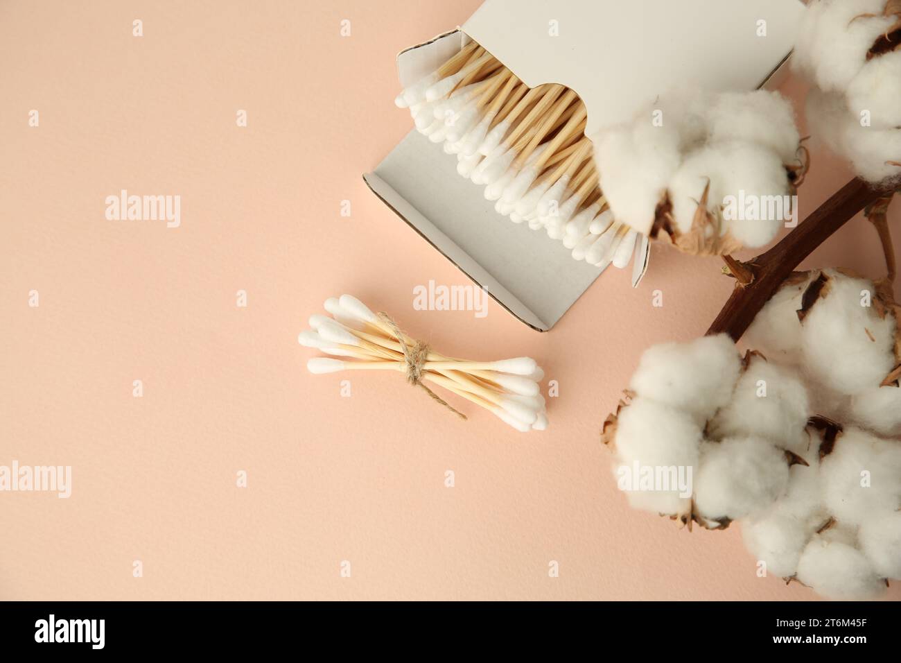 Cardboard box with cotton buds and flowers on beige background, flat ...