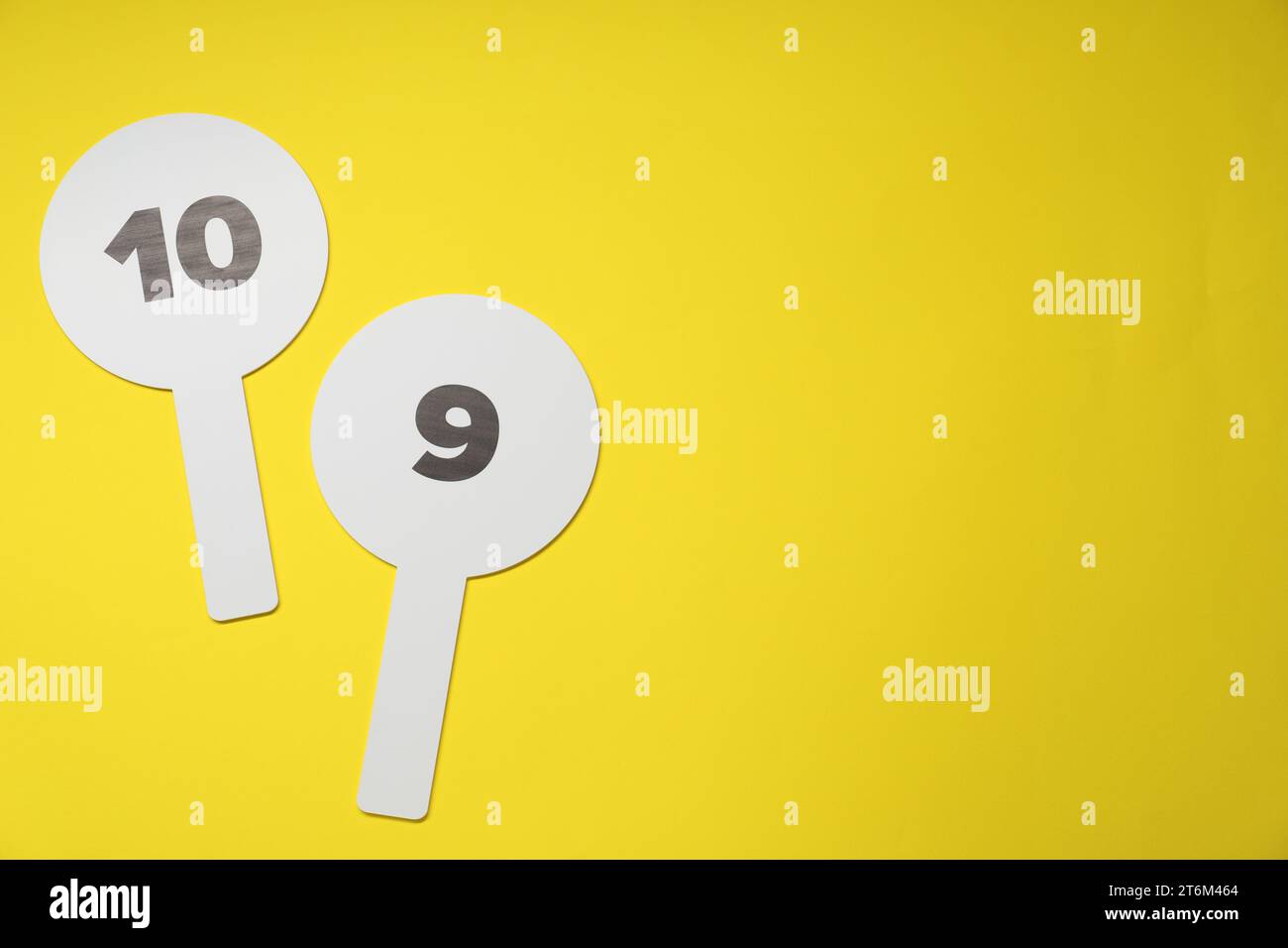 Auction paddles with numbers on yellow background, flat lay. Space for ...