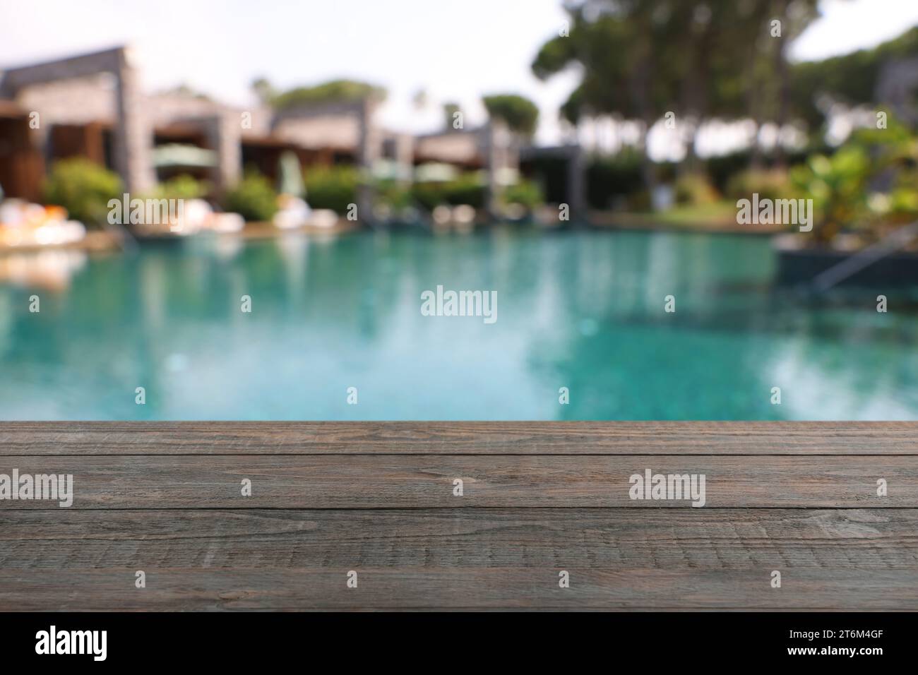 Empty wooden desk near outdoor swimming pool at resort, space for ...