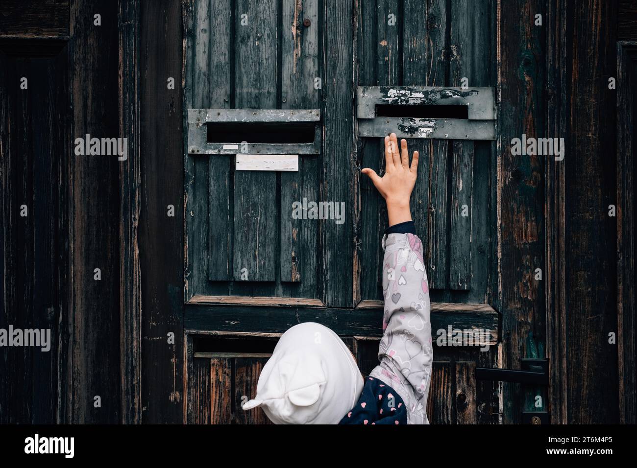Child touching on old city door. Girls hand near wooden dark doors ...