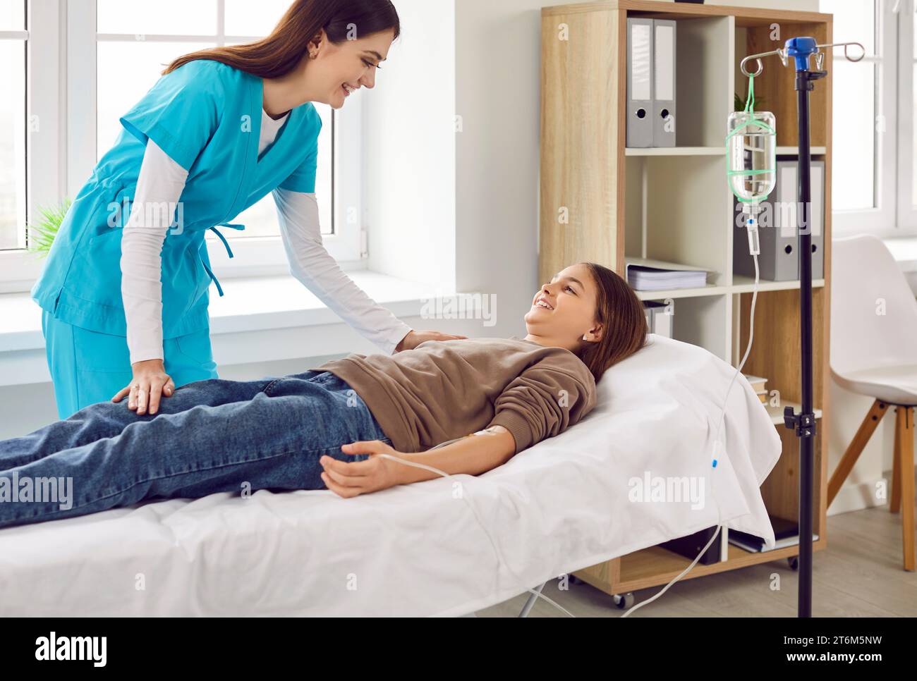 Teenage child girl lying on couch in clinic while receiving IV drip ...