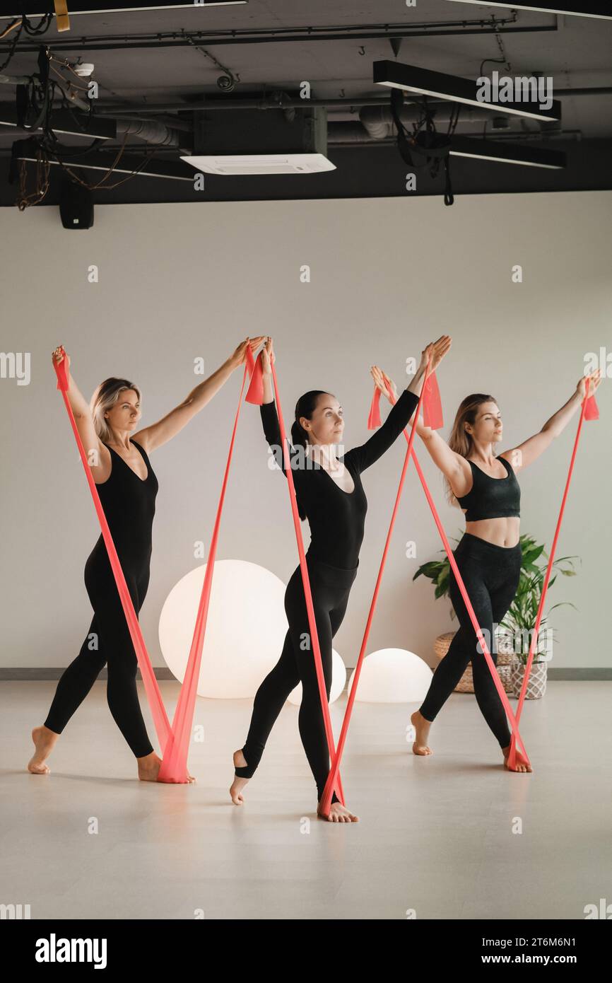 Girls in black are doing fitness with red ribbons indoors Stock Photo ...