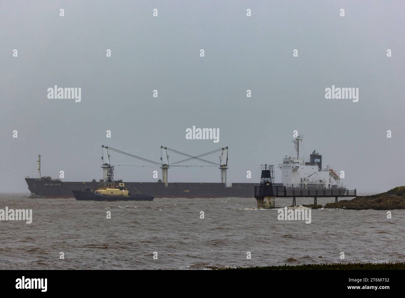 Murky squalle weather bulk carrier heading out to sea Stock Photo - Alamy