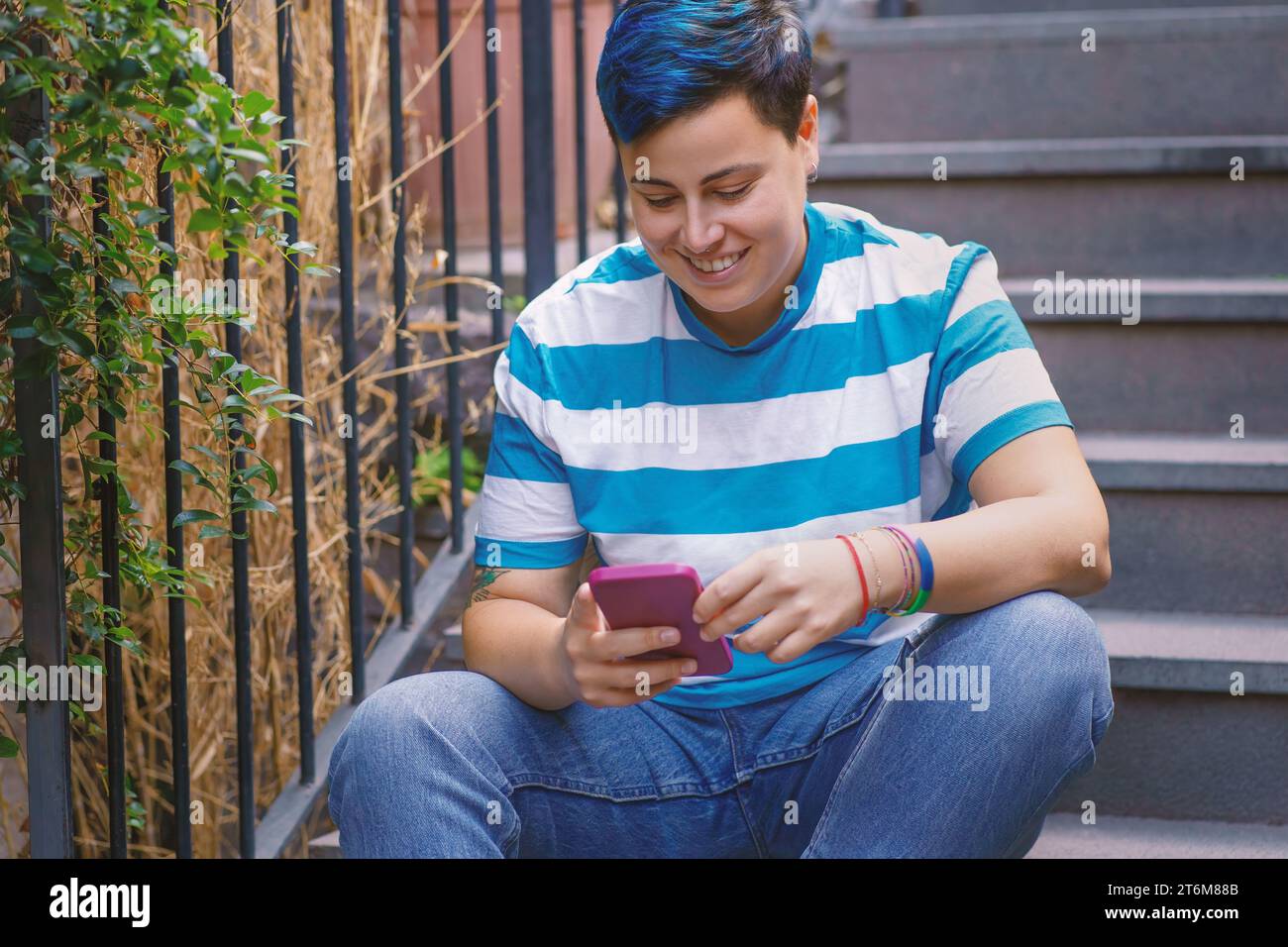 Non-binary person in striped attire engaged with smartphone ...