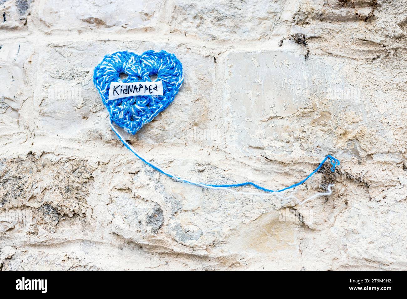 Knitted blue heart with the inscription kidnapped on a stone wall ...