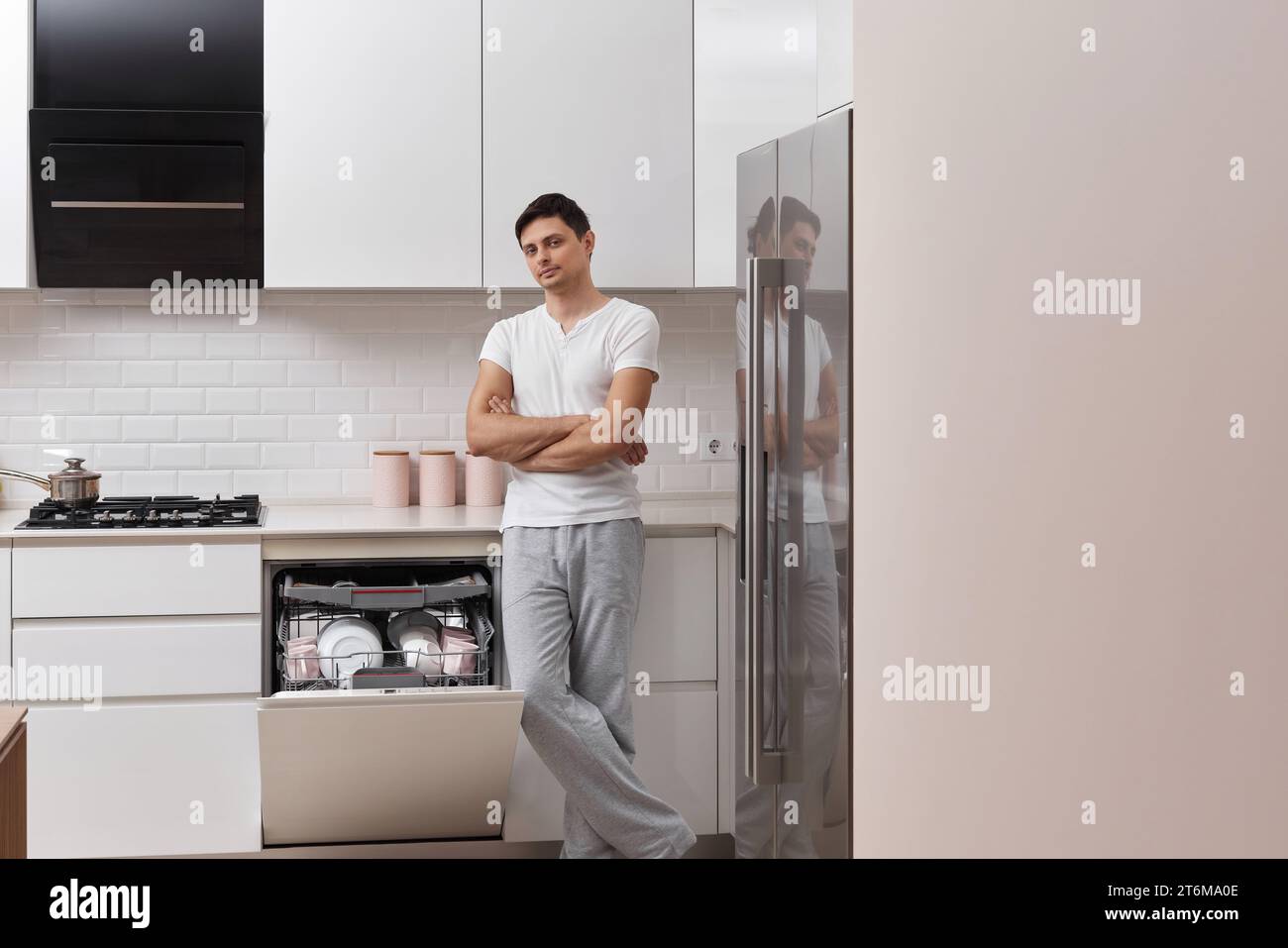 handsome guy using dishwasher and washing dishes in white modern ...