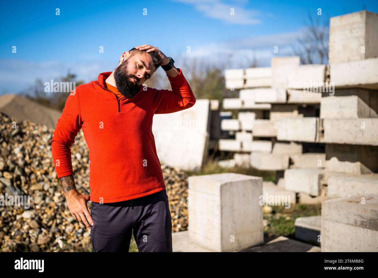 Adult man is exercising outdoor on sunny day. He is stretching his body ...