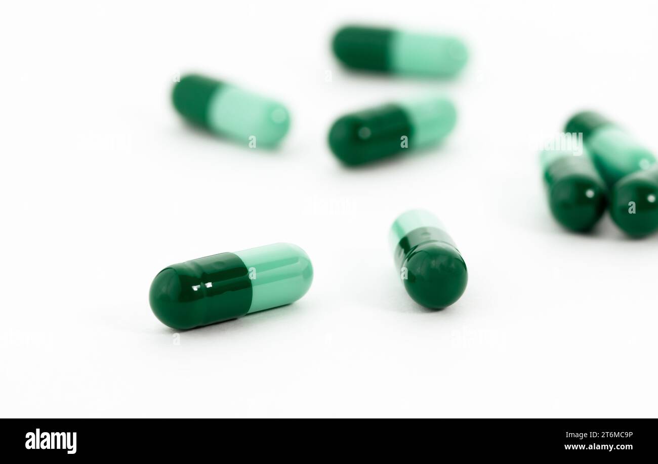 Selective focus on green capsules pill spread on white background ...