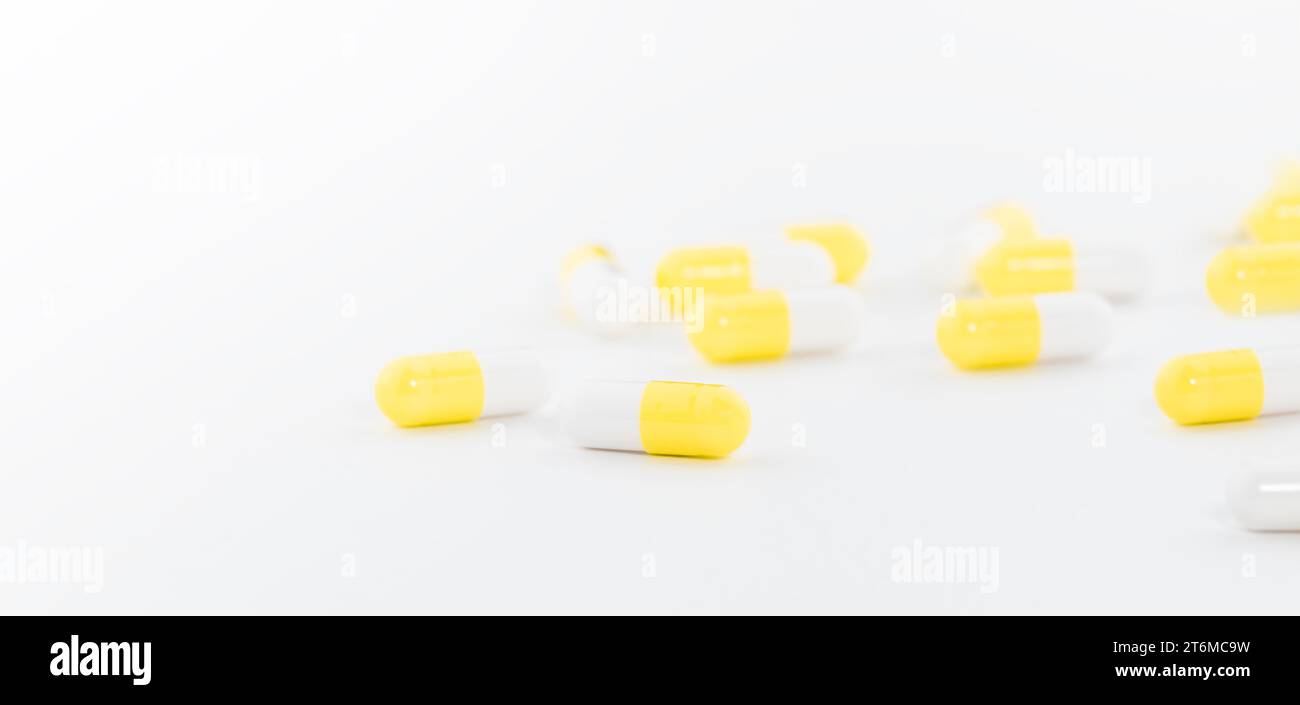 Yellow and white capsules pill spread on white background with shadow ...