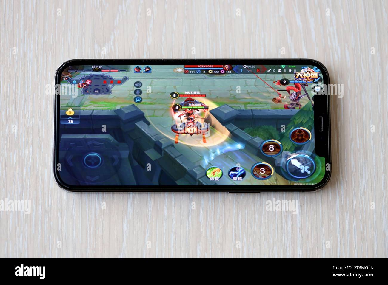 Honor of Kings mobile iOS game on iPhone 15 smartphone screen on wooden ...