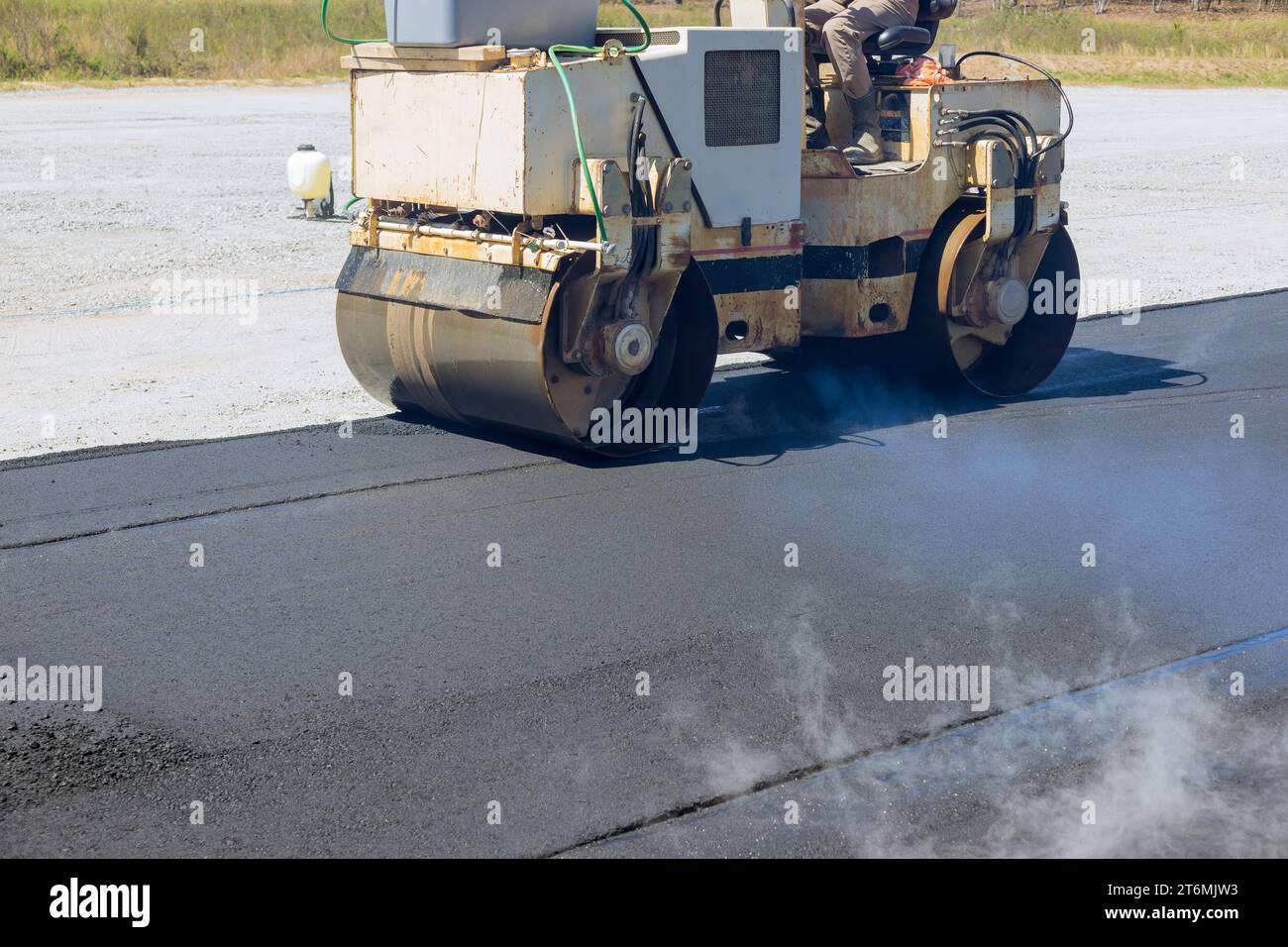 Worker uses asphalt roller vibratory is laying asphalt to new road ...