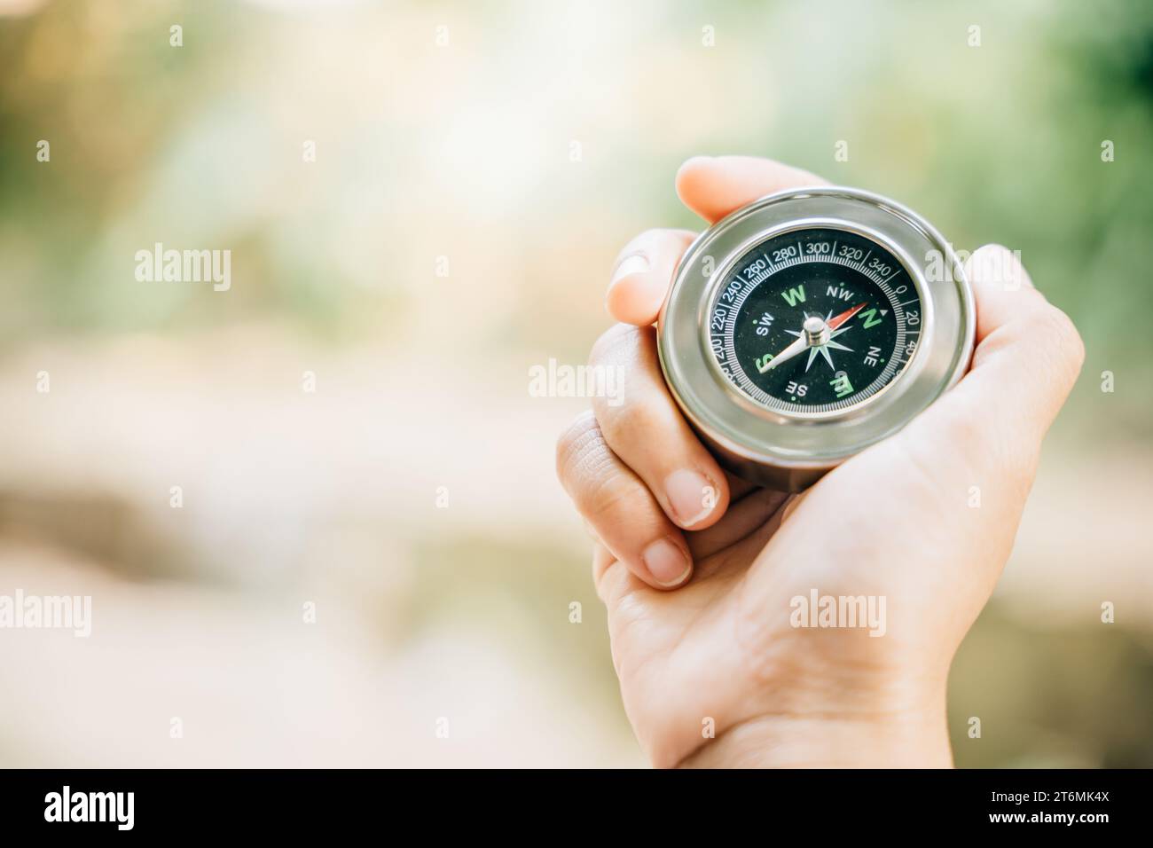 Hiker searches for direction in the forest holding a compass to ...
