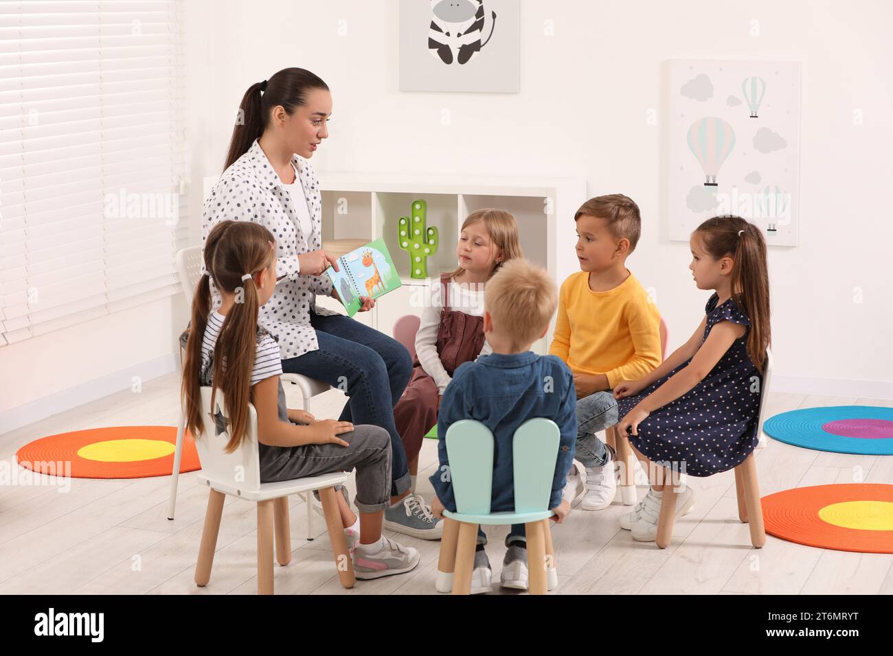 Nursery teacher and group of cute little children learning animals in ...