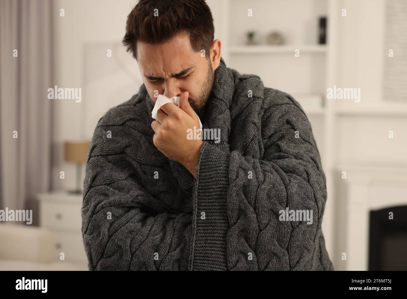 Sick man wrapped in blanket with tissue blowing nose at home. Cold ...