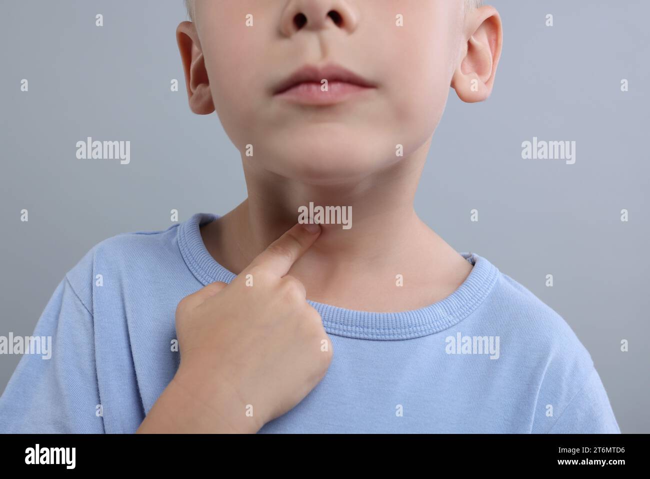 Endocrine system. Little boy doing thyroid self examination on light ...