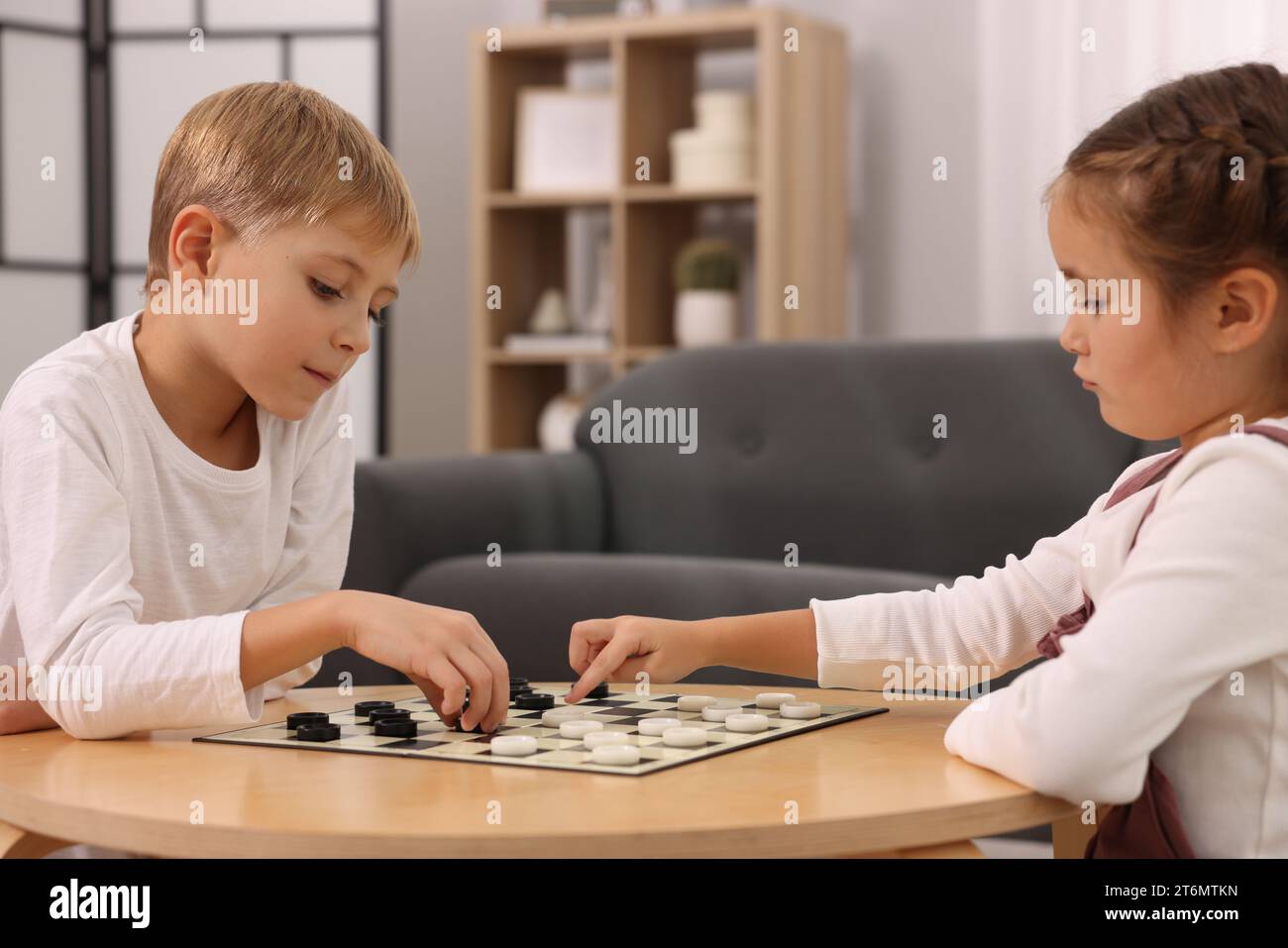 Children playing checkers at coffee table in room Stock Photo - Alamy