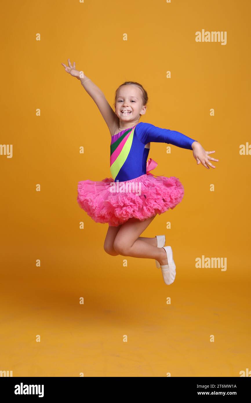 Cute little dancer in costume jumping on orange background Stock Photo ...