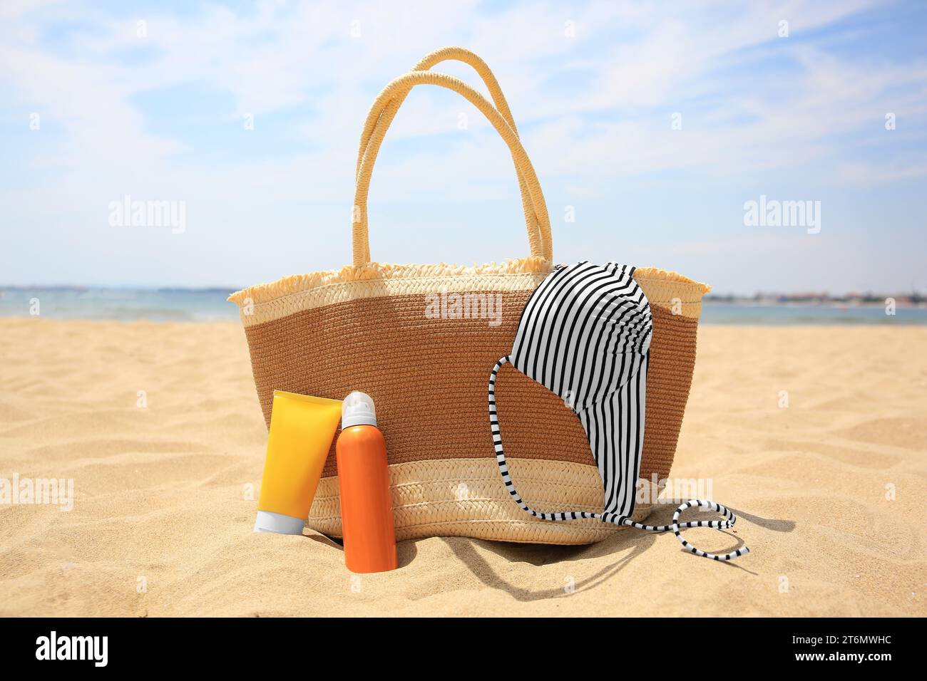 Sunscreens, bag and swimsuit top on sandy beach. Sun protection Stock ...