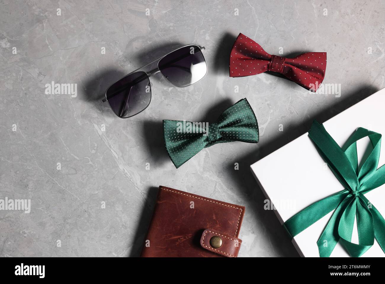 Stylish color bow ties, box, wallet and sunglasses on gray marble ...