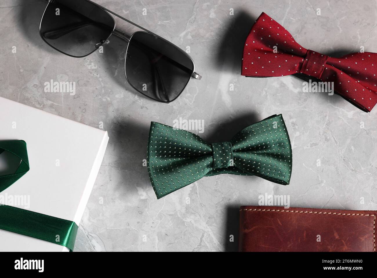 Stylish color bow ties, box, wallet and sunglasses on gray marble ...