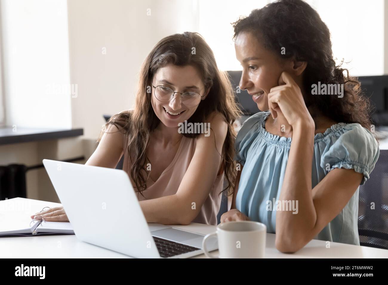 Two happy engaged office colleague women using laptop together Stock ...