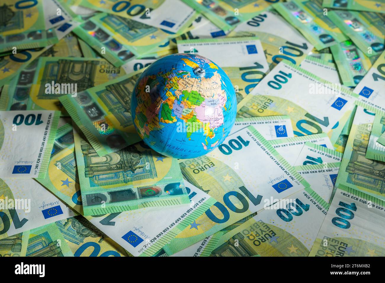 A little globe map lying on an assortment of euro money bills. High ...