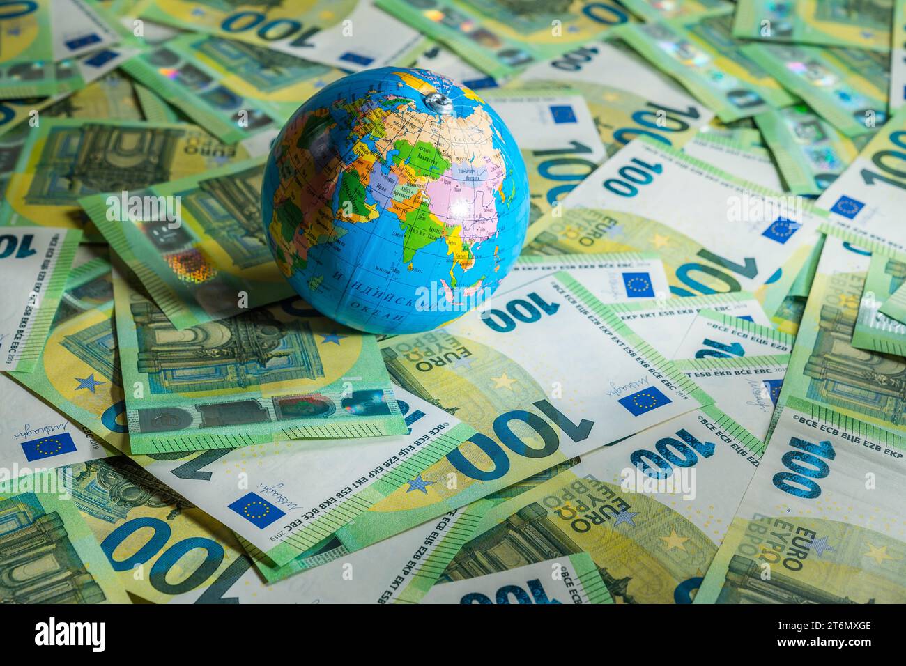 A little globe map lying on an assortment of euro money bills, front ...