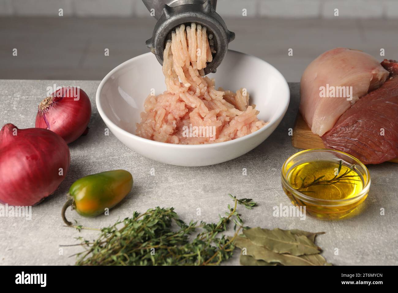 Metal meat grinder with chicken mince and different products on light ...
