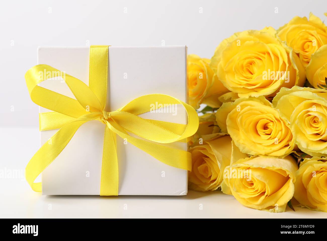 Beautiful bouquet of yellow roses and gift box on white background ...