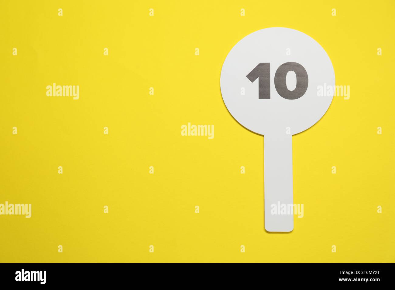 Auction paddle with number 10 on yellow background, top view. Space for ...