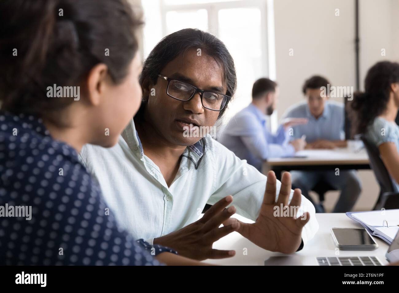 Serious adult Indian businesspeople talking at workplace, collaborating ...