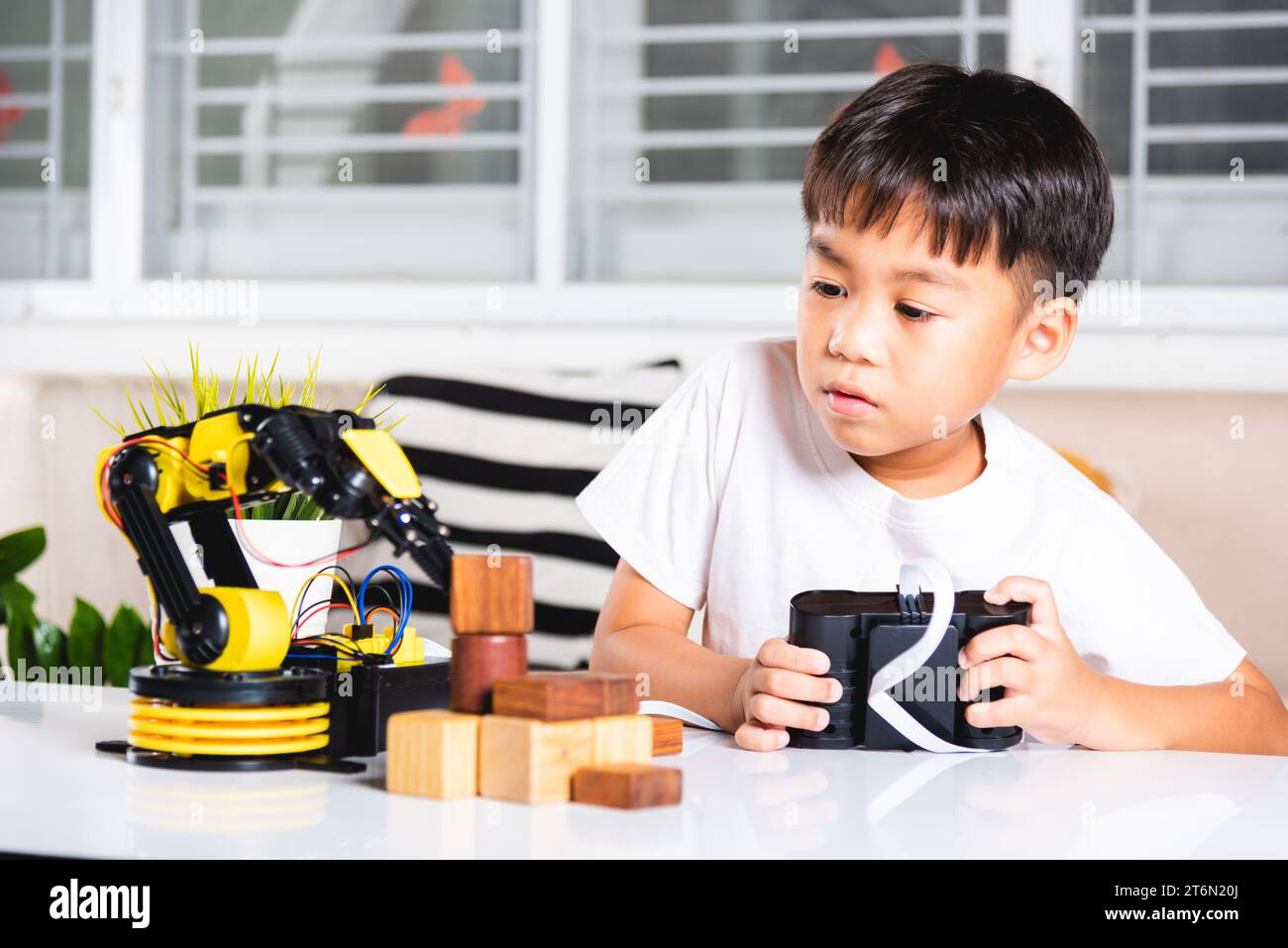 Happy Asian little kid boy using remote control playing robotic machine ...