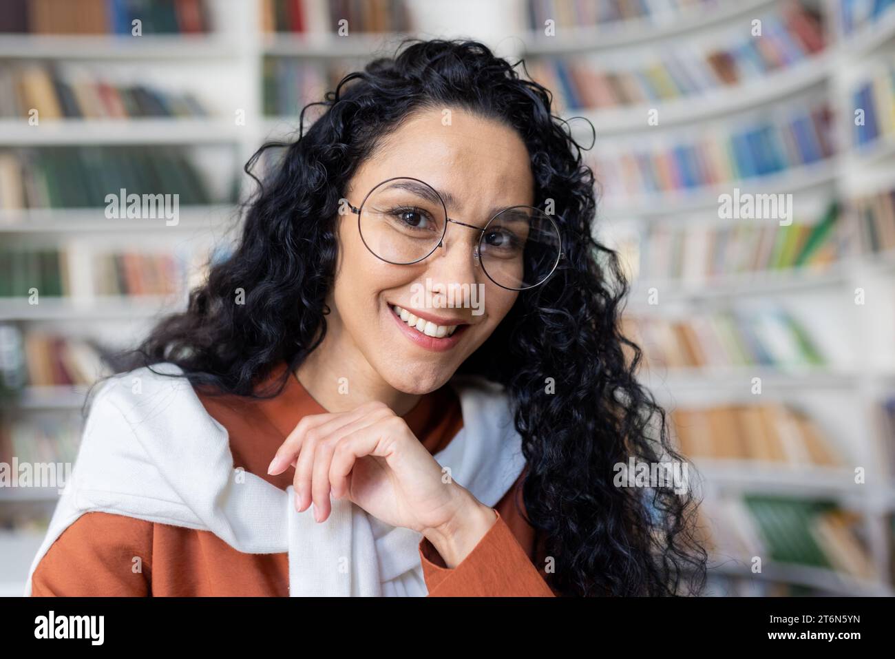 Portrait of happy young Indian female teacher sitting in school ...