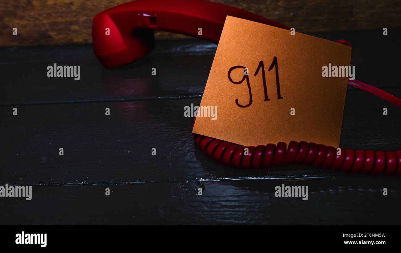 Writing 911 on memo post reminder. sticky paper surrounded by wire of ...