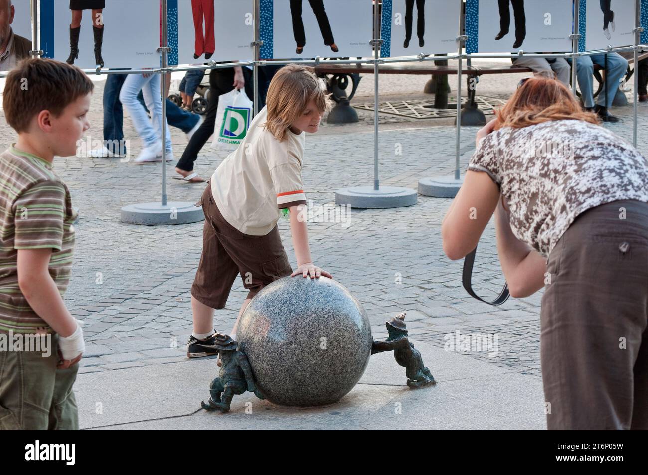 Mom taking pictures of child at sculpture of Ball-pushing and lifting ...