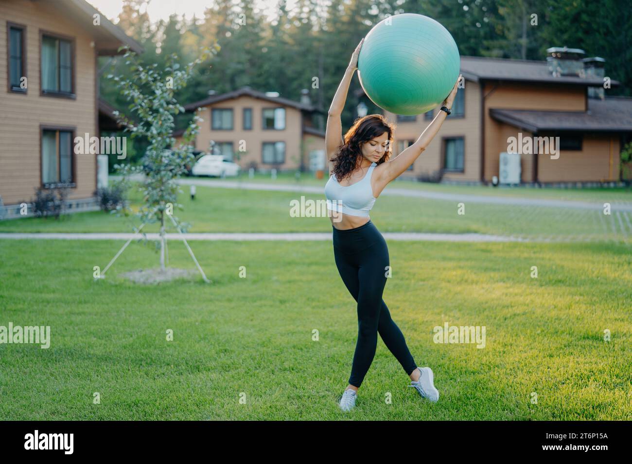 Radiant fitness enthusiast lifts a large exercise ball in the golden ...
