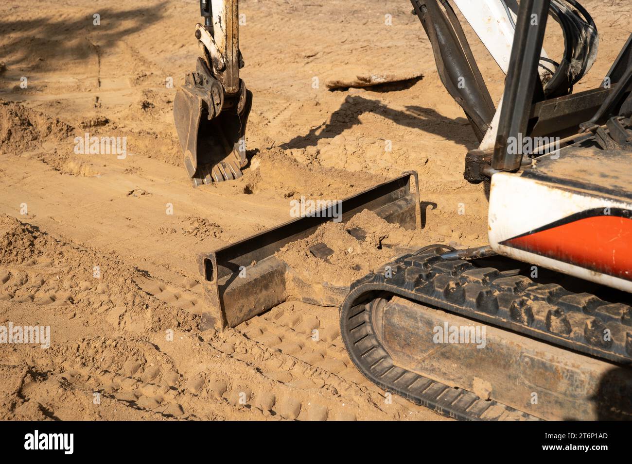 A mini excavator parked on brown dirt with closeup view of the bucket ...