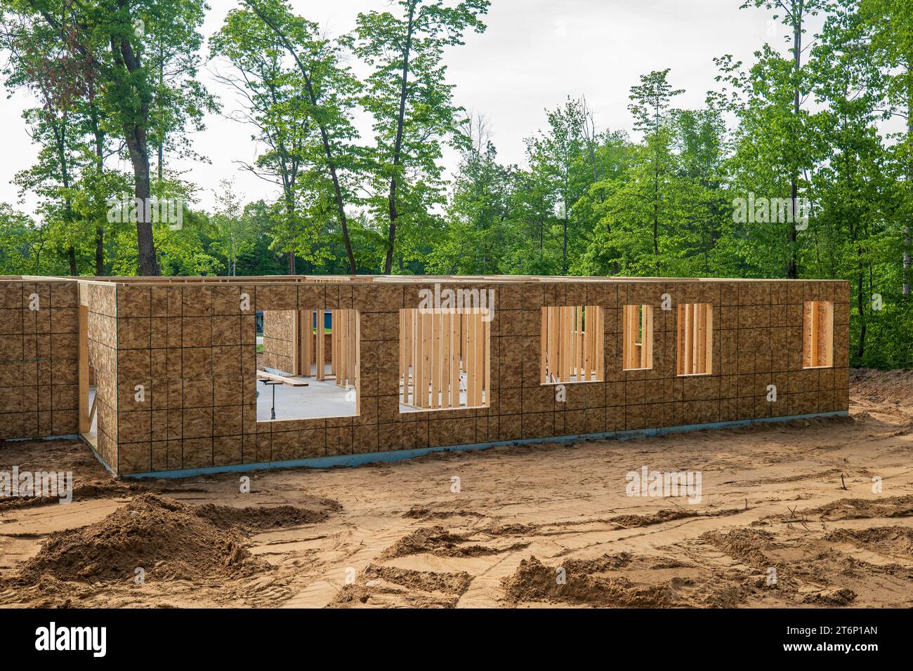 New home building site in early construction stage, with plywood on exterior walls with window ...