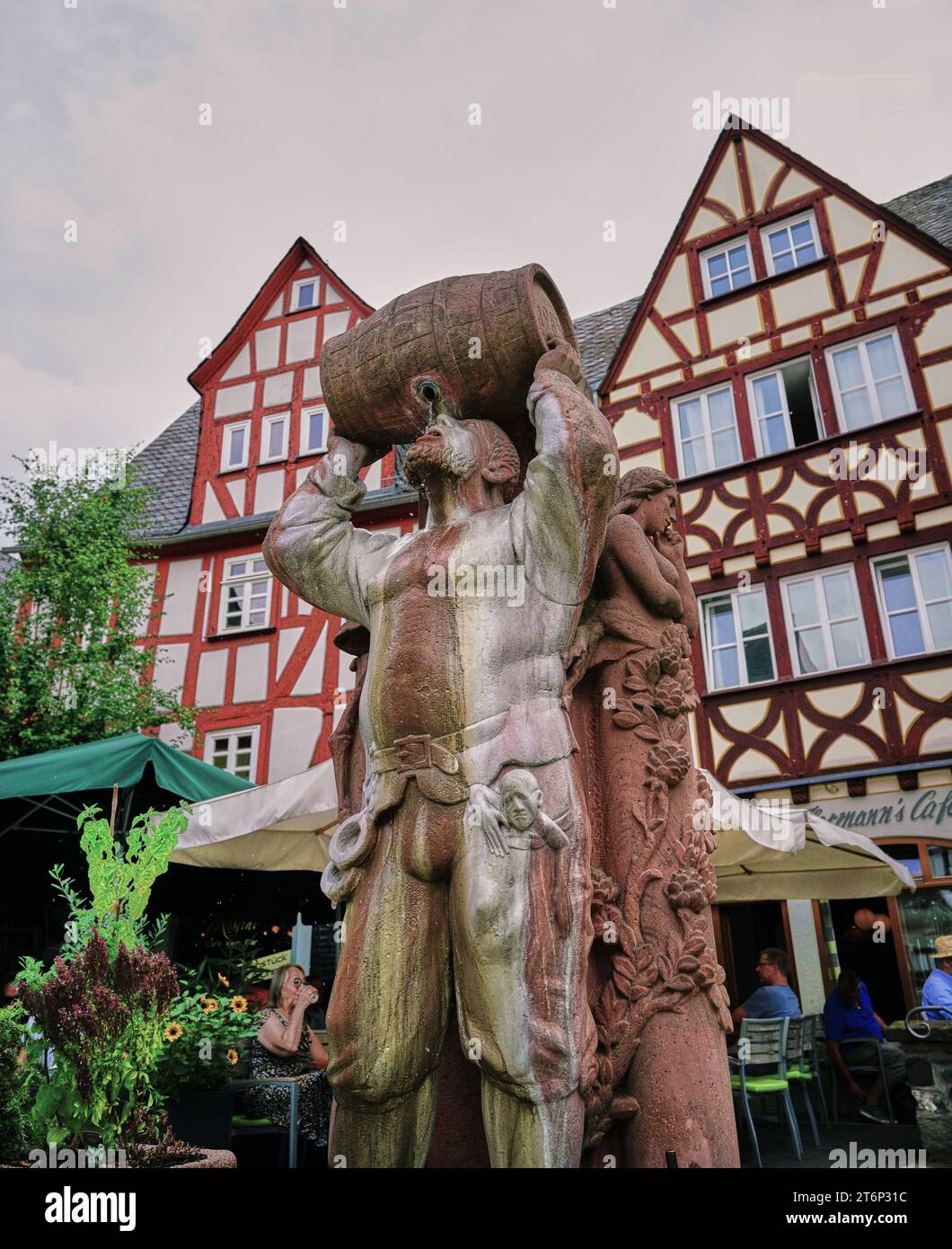 Larger than life statue of a man drinking wine from a barrel hoisted ...