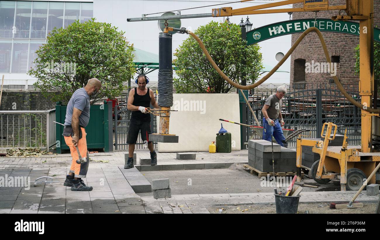 Skilled stone layers put down a new sidewalk at a construction site ...