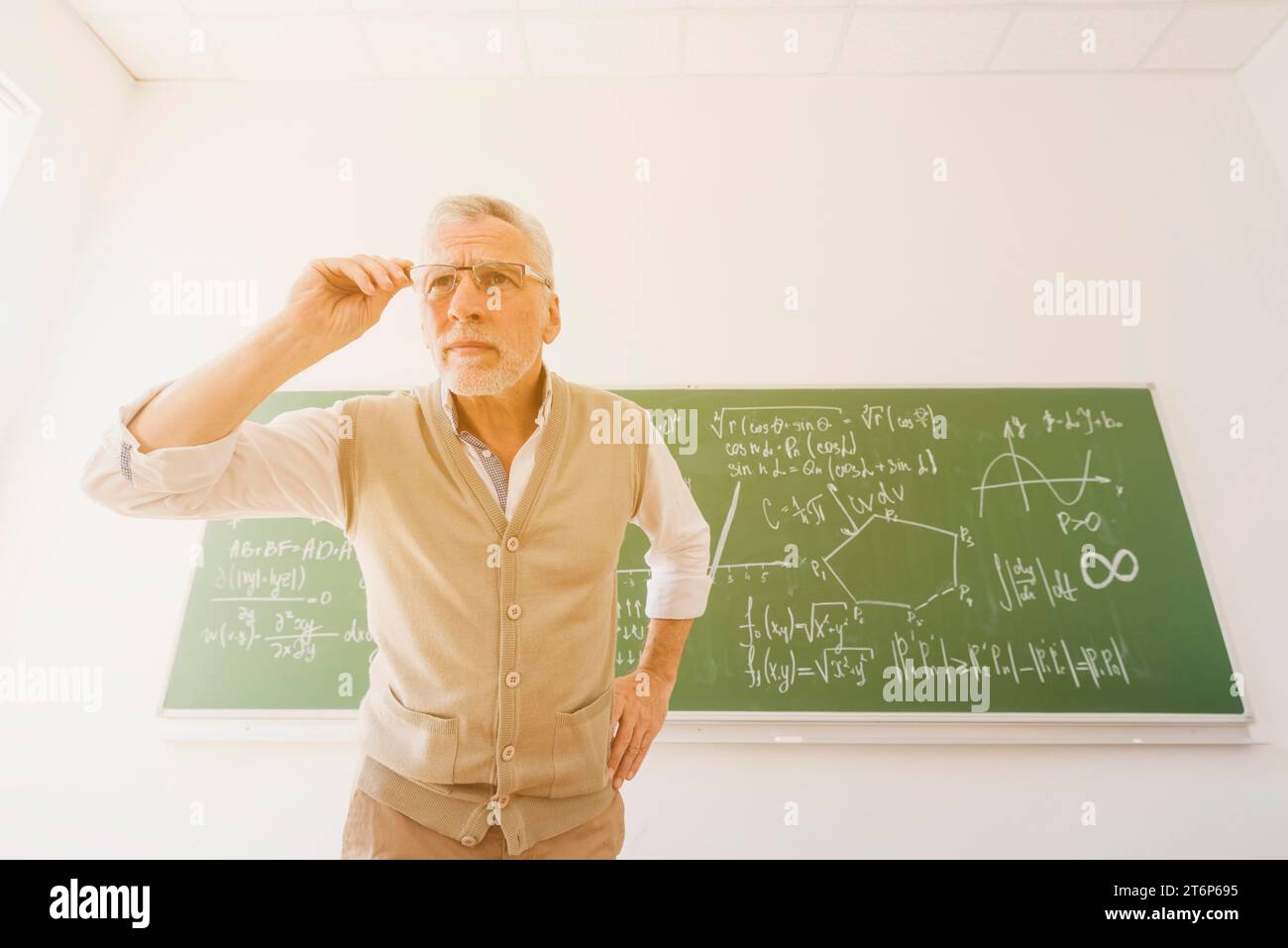 Aged professor looking through glasses classroom Stock Photo - Alamy