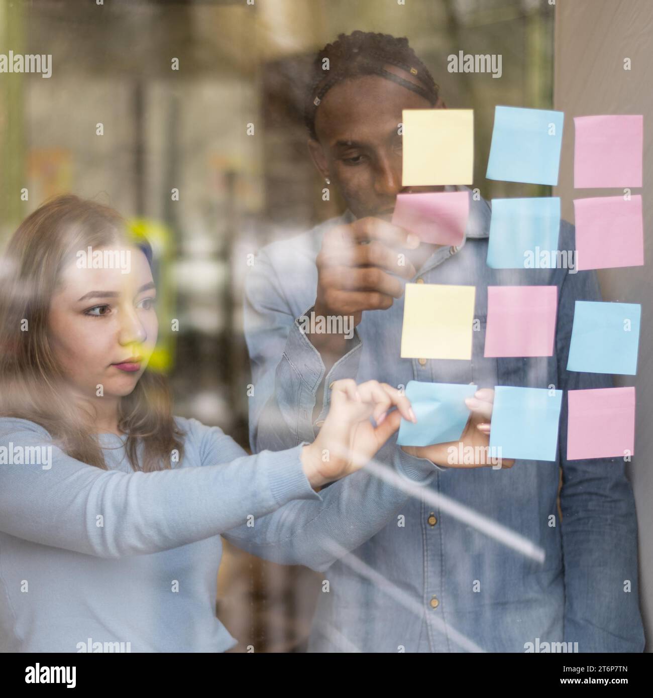 Front view man woman putting sticky notes office window Stock Photo - Alamy