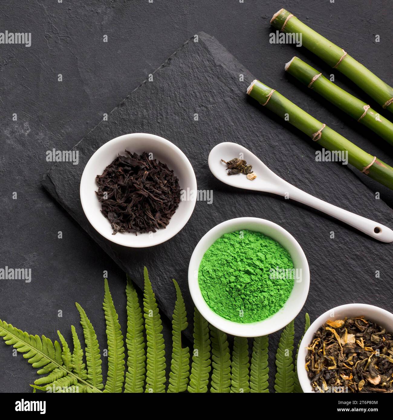 Green matcha tea dry tea herb with bamboo stick black stone background ...