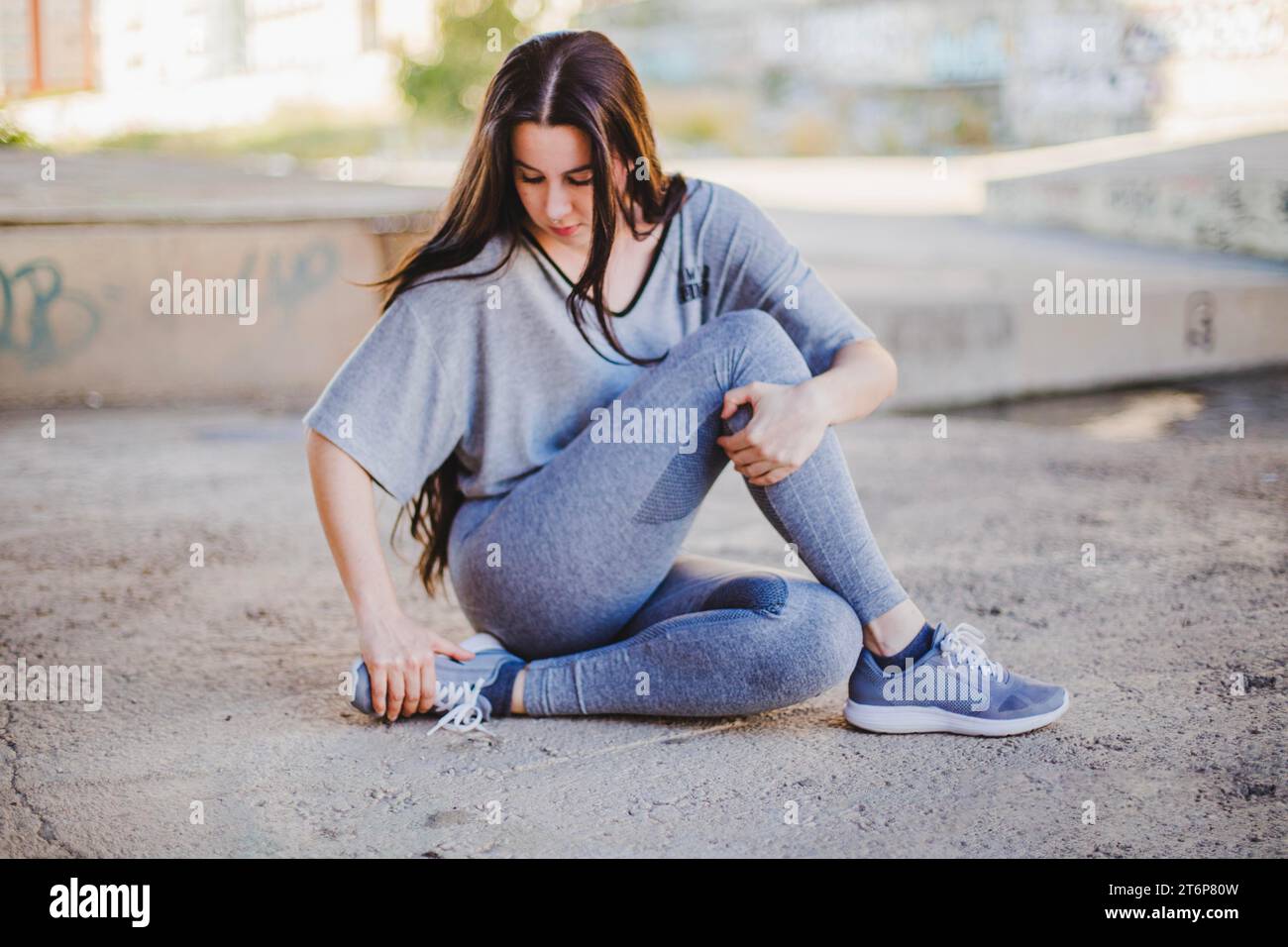 Girl sitting concrete floor stretching Stock Photo - Alamy