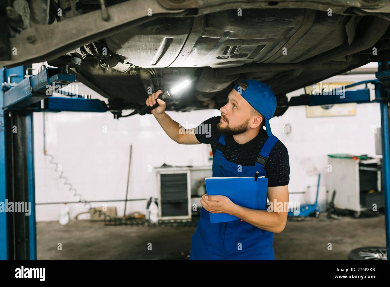 Mechanic checking bottom car Stock Photo - Alamy