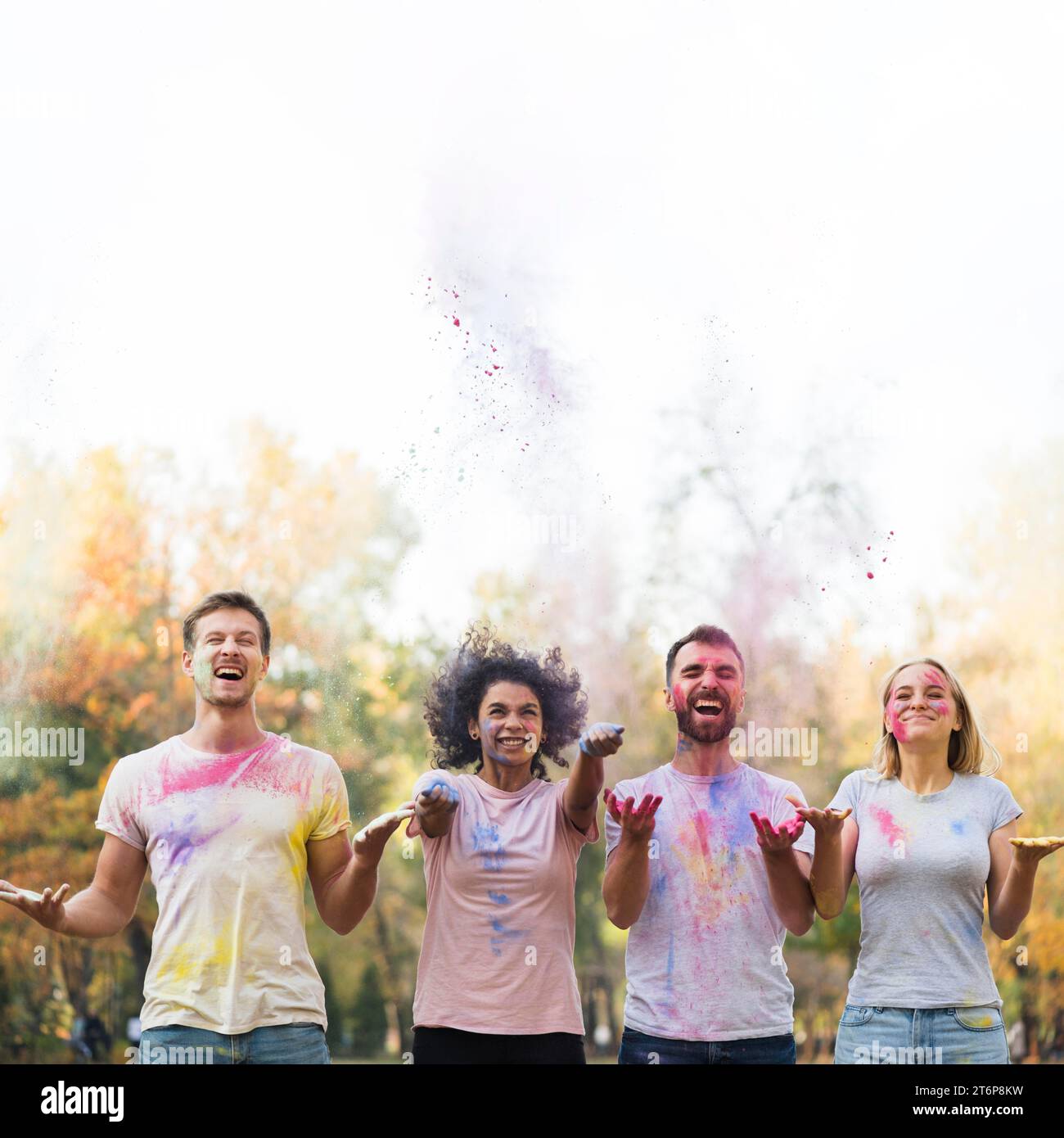 Medium shot friends throwing paint holi Stock Photo - Alamy