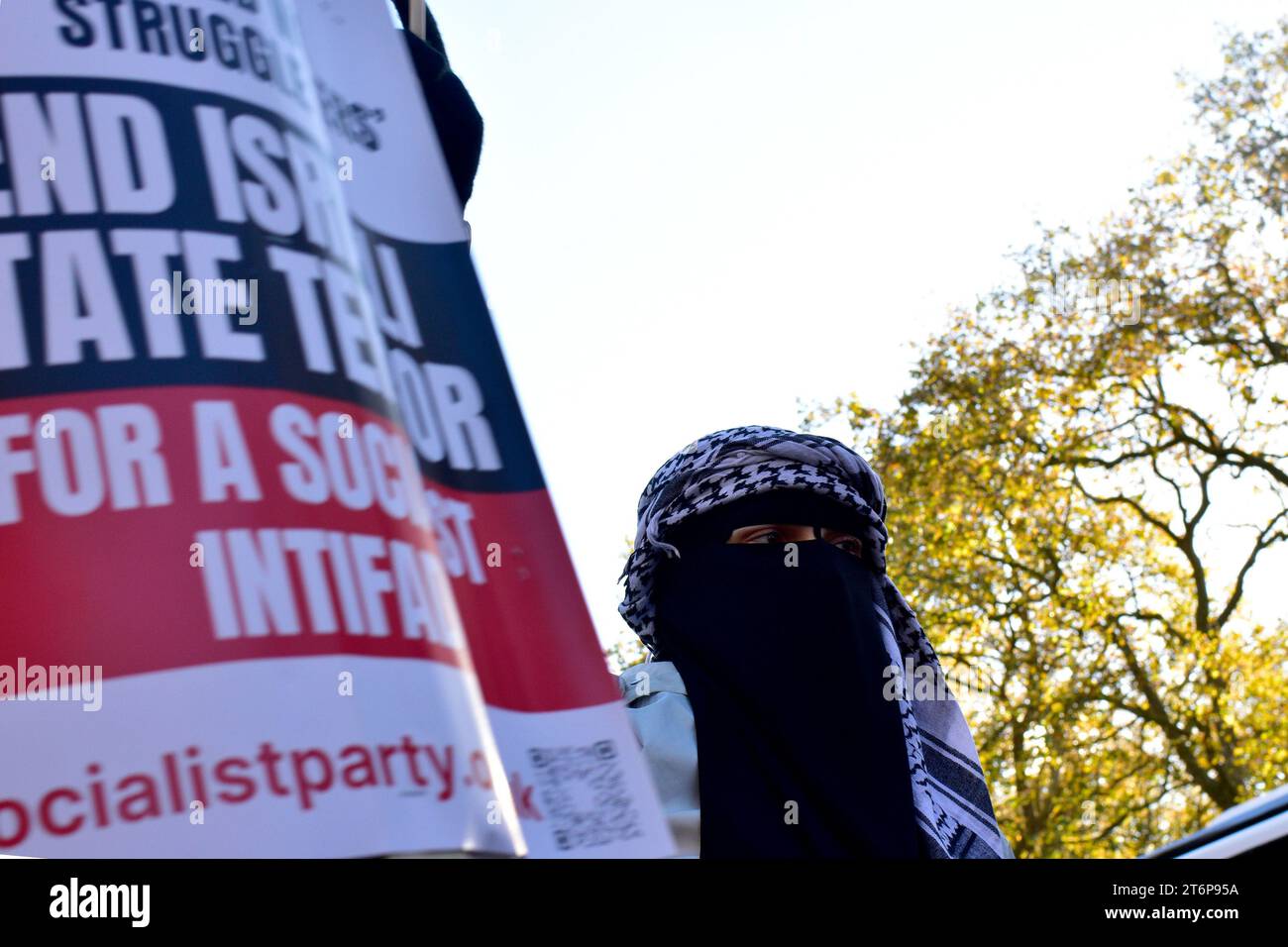 Woman in burka stands above the roadside alongside a plaque calling for ...