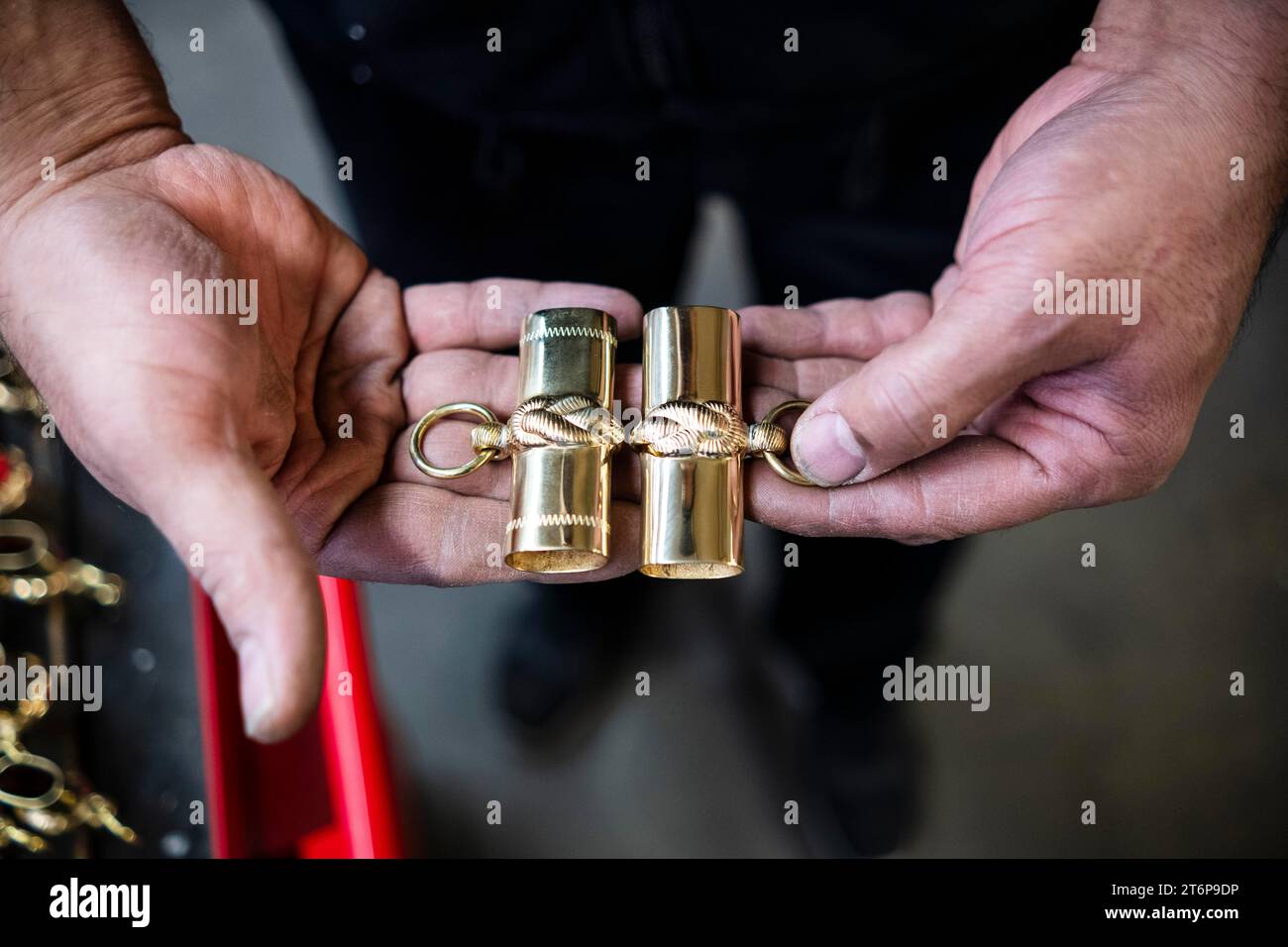 Two hands holding polished casings for the scabbards of edged weapons ...